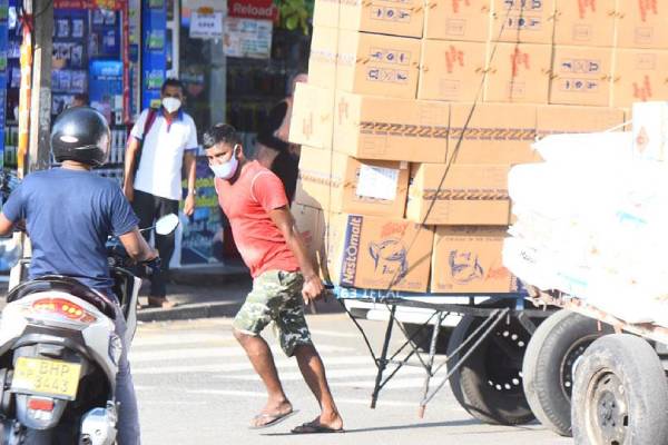 A worker pulling a hand-cart laden with goods