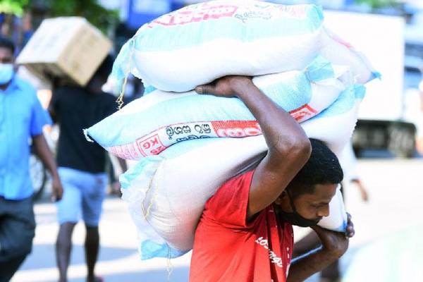 A worker pulling a hand-cart laden with goods