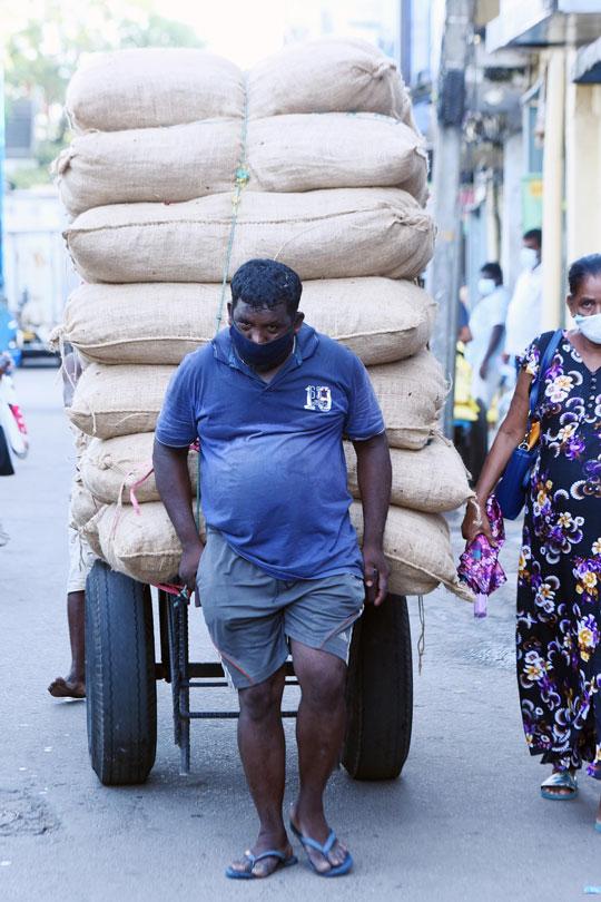 A worker pulling a hand-cart laden with goods