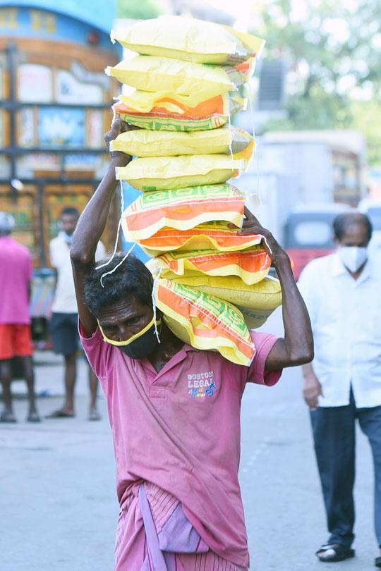 A worker pulling a hand-cart laden with goods