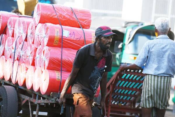 A worker pulling a hand-cart laden with goods