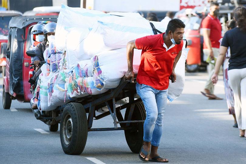 A worker pulling a hand-cart laden with goods